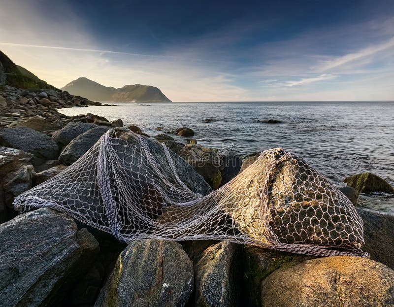 A Torn Net Tangled Around Jagged Rocks on a Shoreline, Representing ...