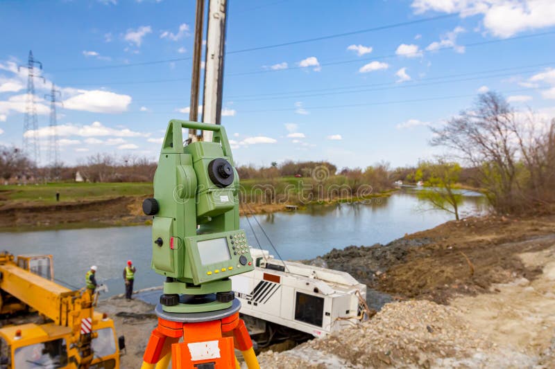 Total Station in Front of Mobile Crane and Drilling Machine Working ...