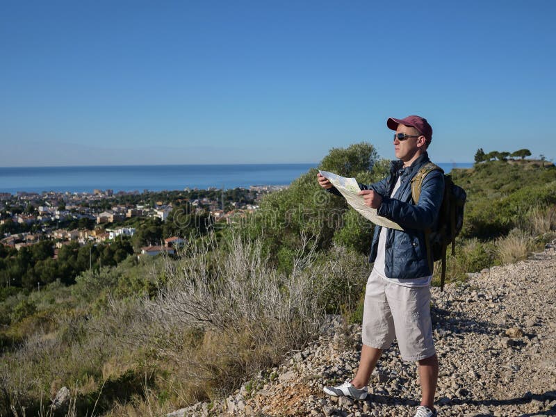 Tourist Guy with a Map of the Area Stands on a Stone Path on a Hill ...
