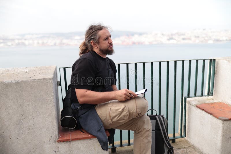 Tourist Sitting on Bench Overlooking Lisbon, Portugal, Taking Notes ...