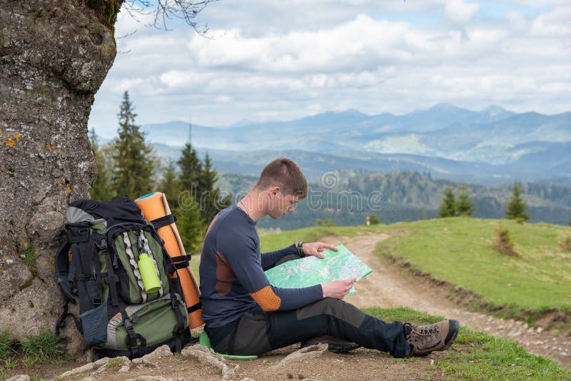 Tourist is Studying a Map of the Area Sitting Under a Tree by the Road ...