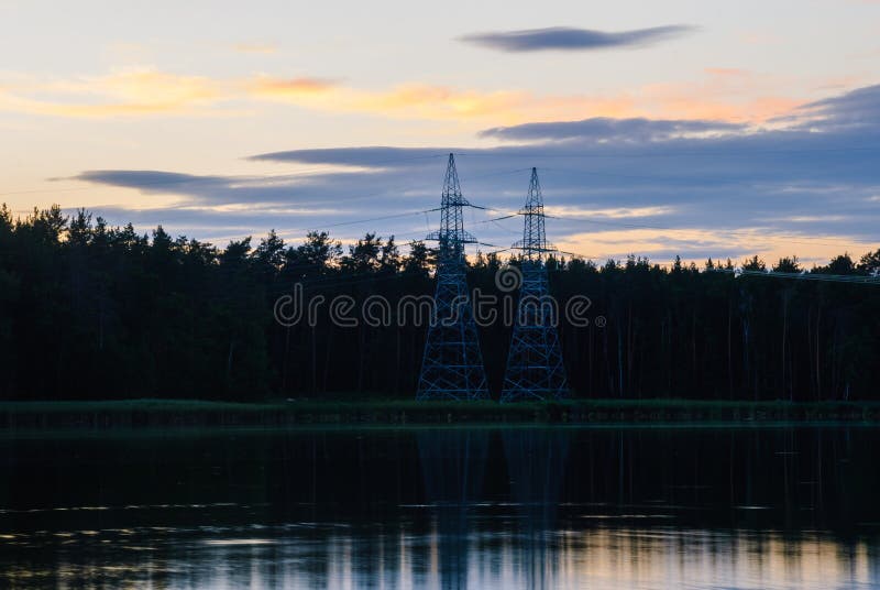 Towers of Power Lines on the Lake, Against the Backdrop of the Sunset ...