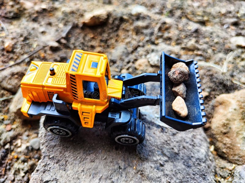 Toy Yellow Tractor or Excavator with a Bucket during Operation. Road or ...