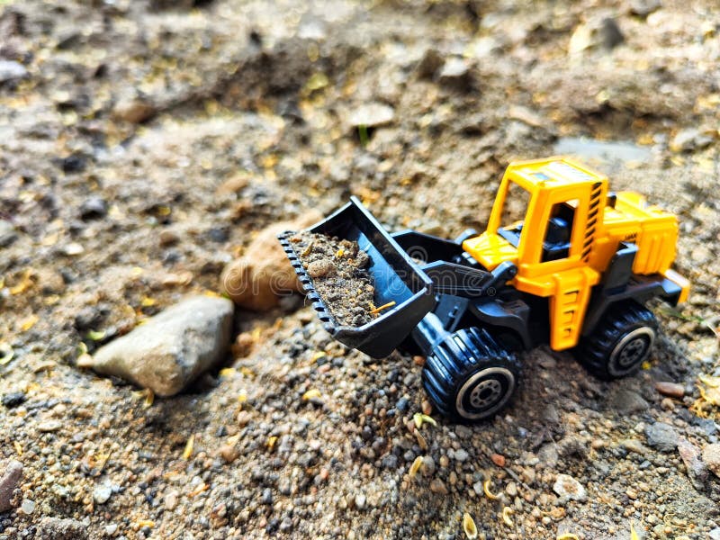 Toy Yellow Tractor or Excavator with a Bucket during Operation. Road or ...