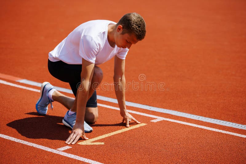 A Track Runner is Standing at the Starting Line, Getting Ready for a ...