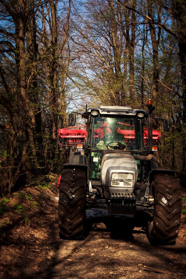 Tractor on Big Wheels on Soil Road in Spring Forest Stock Photo - Image ...
