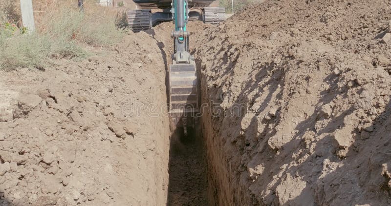 A Tractor Digs a Trench in the Ground. Construction Work and ...