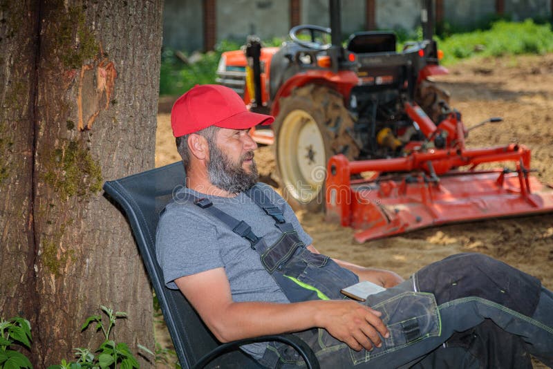Tractor Driver Rests in the Shade of a Tree after Plowing the Land ...