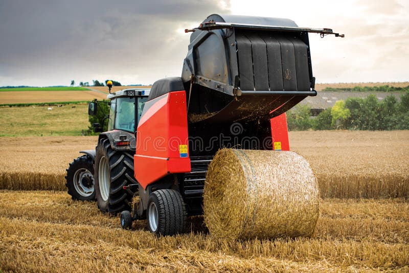 Tractor Equipped with a Baler for Making Round Straw Bales in Action in ...