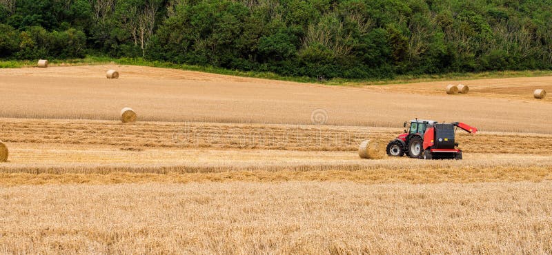 Tractor Equipped with a Baler for Making Round Straw Bales in Action in ...
