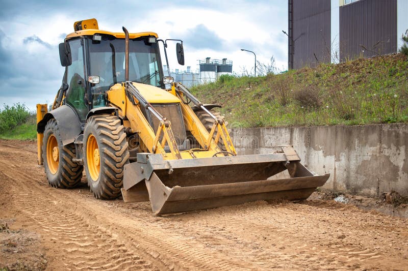 A Tractor or a Loader is Parked on a Dirt Road, Surrounded by Fields ...