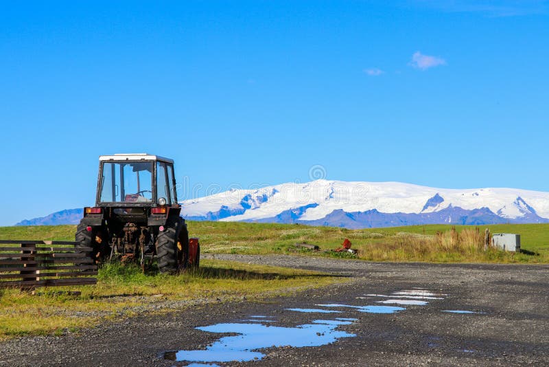 Tractor Parked on the Grass Against a Snow-covered Mountain Stock Image ...