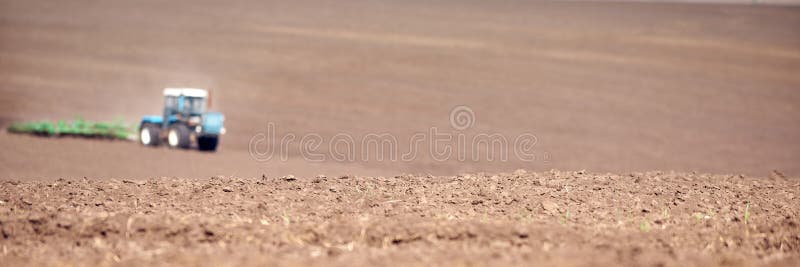 A Tractor Plowing and Sowing in the Field. Panoramic Format Stock Photo ...