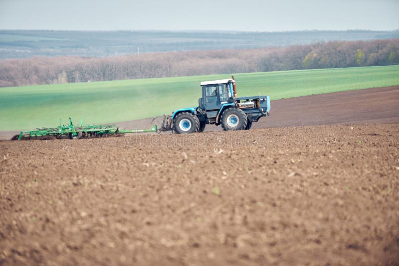 A Tractor Plowing and Sowing in the Field. Panoramic Format Stock Photo ...