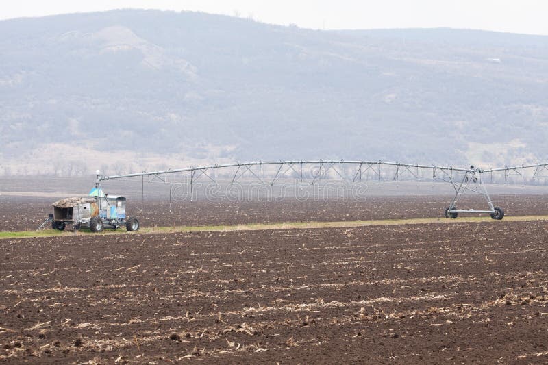 A Tractor Plows a Field with Irrigation System Under a Vast Sky Stock ...