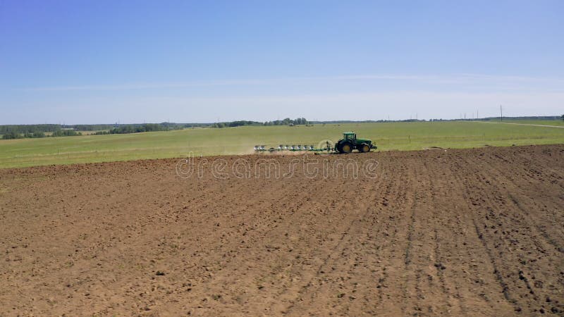 Tractor Plows the Field by Plow, Plowing Fields. Farmer Preparing the ...