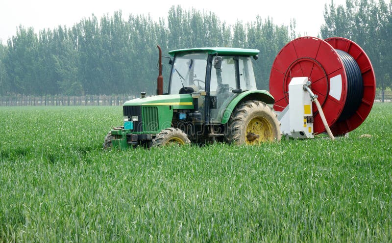 A Tractor Pulling a Reel Irrigation Machine in a Wheat Field. Editorial ...