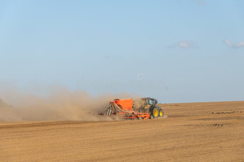 A Tractor Towing a Seeder Creates Dust Clouds while Performing Field ...