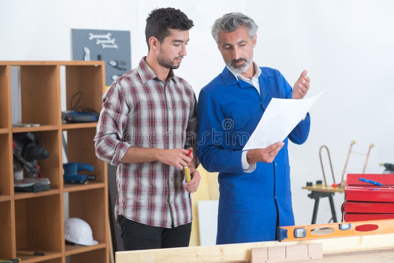Tradesmen Looking at Paperwork in Workshop Stock Image - Image of ...