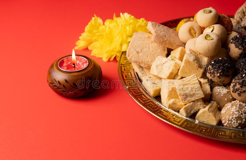 Traditional Indian Sweets On Red Background With Candles And Flowers