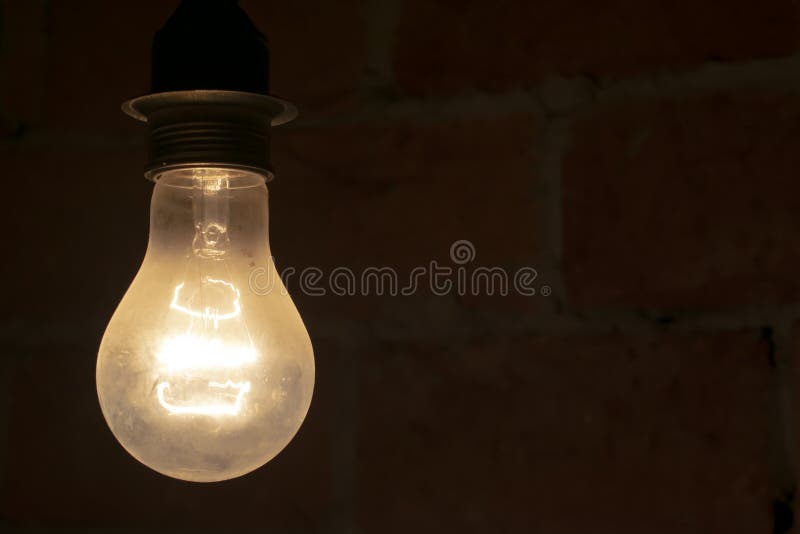 Traditional Light Bulb Glowing in a Dark Room Stock Image - Image of ...
