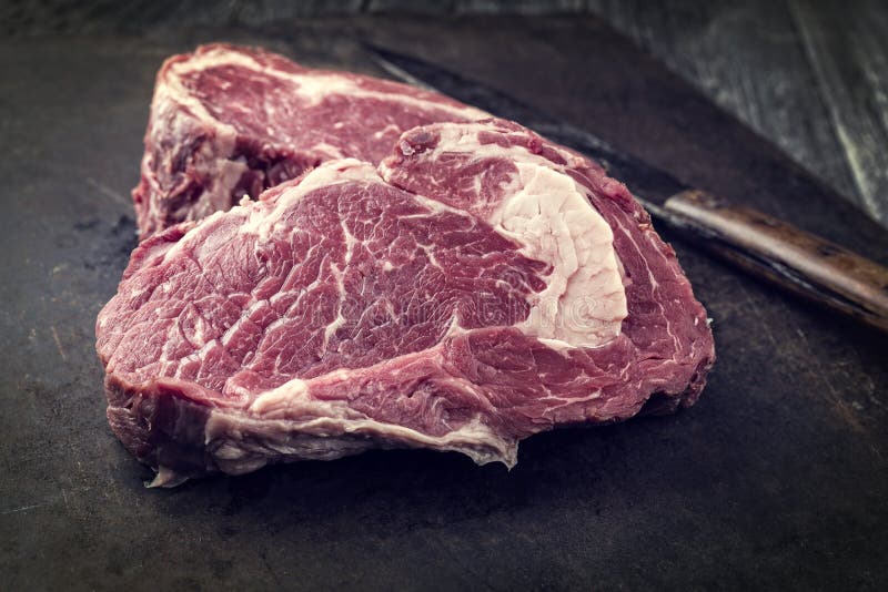 Traditional Raw Angus Rib-eye Beef Steaks on a Rustic Old Board Stock ...