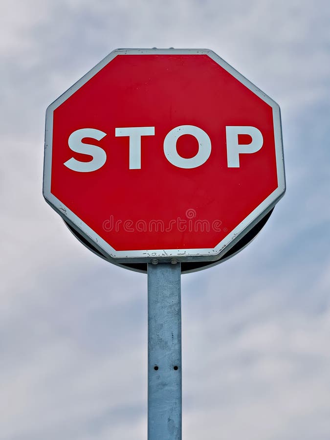 Traffic Stop Sign with White Text on Red Octagon Against Cloudy Sky ...