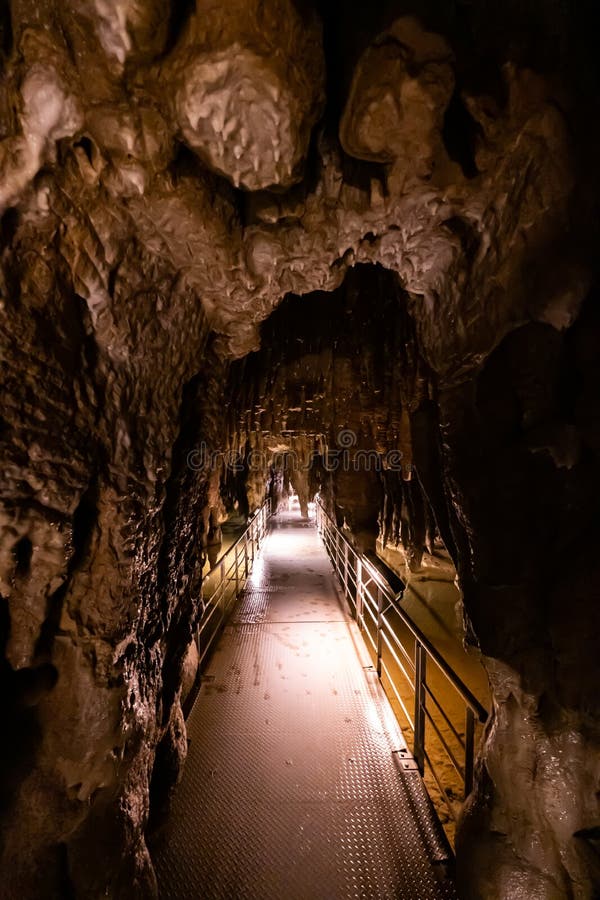 Trail Inside A Dark And Damp Cave. There Are Lighting Attached Along ...
