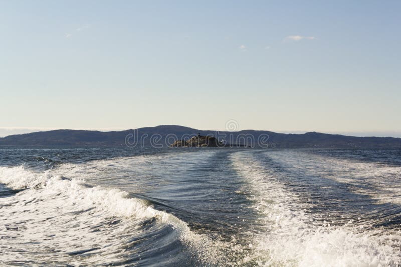 Trail on Water Surface of Fast Moving Boat with Mountains on the ...