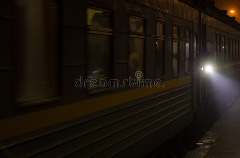 The Train Arrives at the Platform at Night. Bright Rays of Light ...