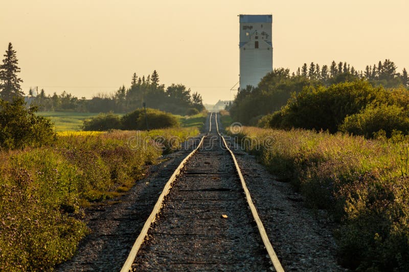 A Train Track Runs through a Field with a Large Grain Silo in the ...
