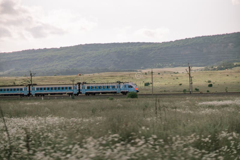 A Train is Traveling through a Field of Grass. the Train is Blue and ...