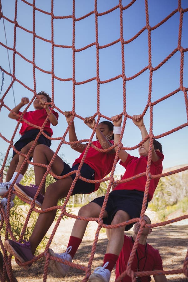 Trainer Assisting Boy To Climb a Net during Obstacle Course Training ...