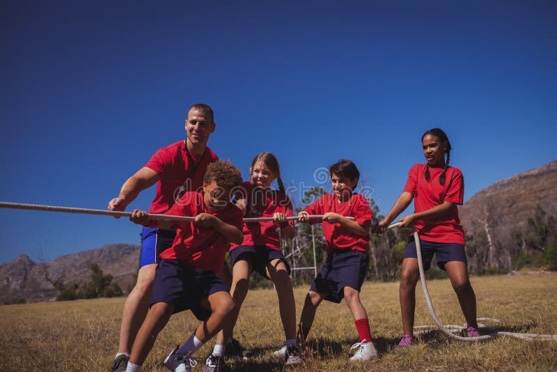 Trainer Assisting Kids in Tug of War during Obstacle Course Training ...