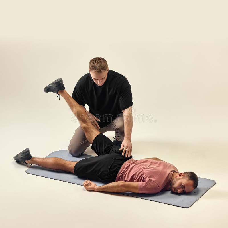 Trainer Assisting Man with Prone Leg Raise, Ensuring Proper Execution ...