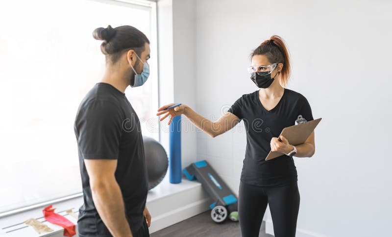 Trainer and Client Discussing Her Progress at the Gym with Mask Stock ...