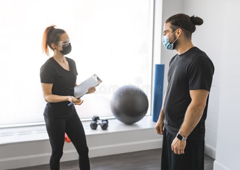 Trainer and Client Discussing Her Progress at the Gym with Mask Stock ...