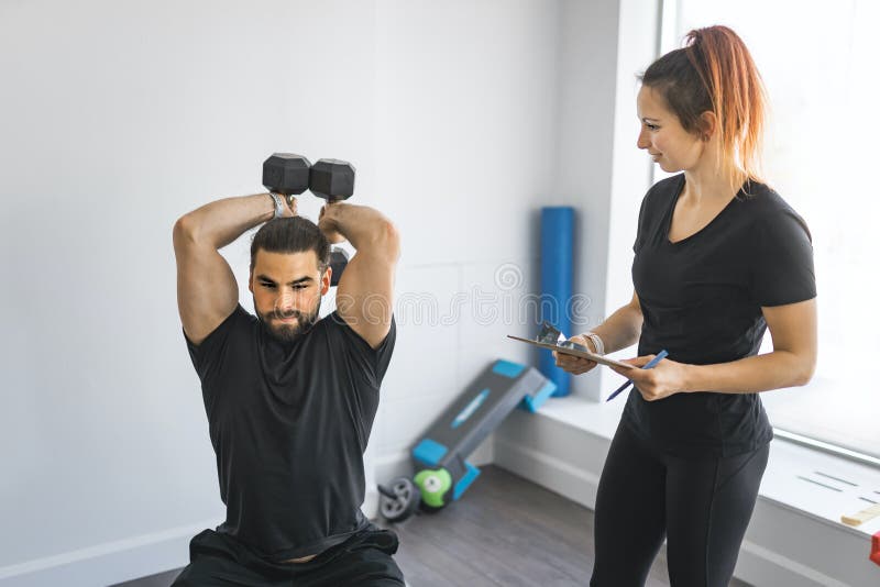 Trainer and Client Training with Dumbbell at the Gym Stock Image ...