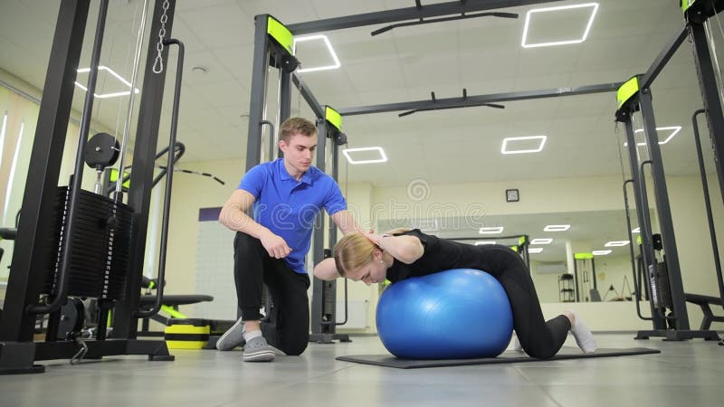 A Trainer is Guiding a Client through Stability Ball Exercises To ...