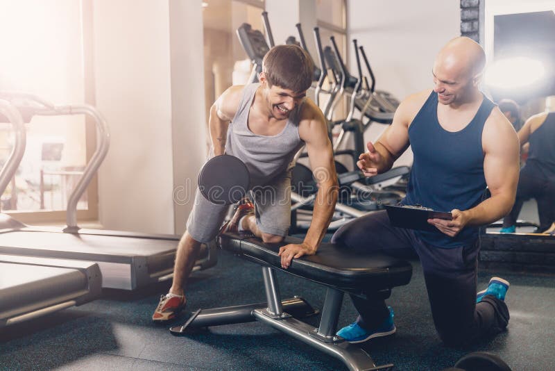 The Trainer Helps the Man Doing the Exercise. Stock Image - Image of ...