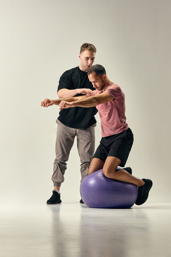 Trainer Instructs Man Balancing on Stability Ball, Engaging Core ...