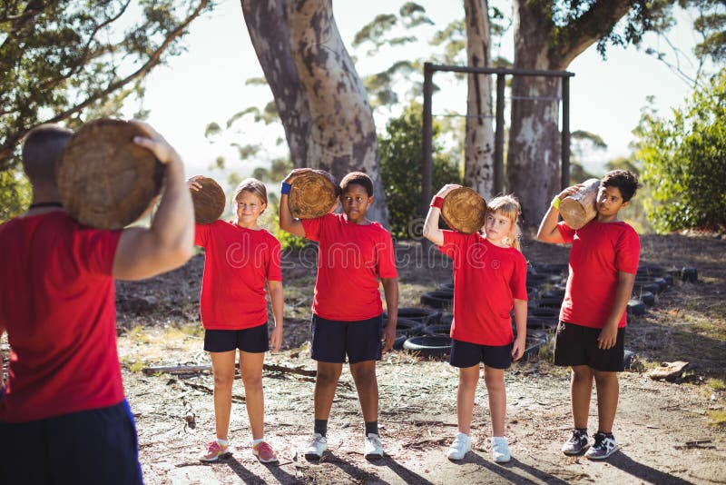 Trainer and Kids Carrying Wooden Logs during Obstacle Course Training ...