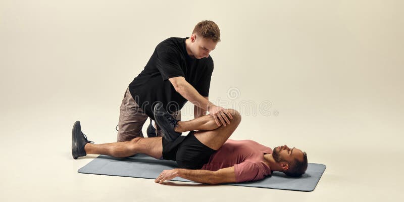 Trainer Pressing Bent Knee while Supporting Lower Back, Helping with ...
