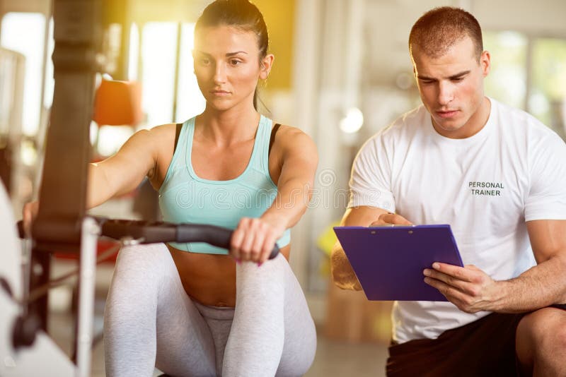 Personal Trainer Helping Young Woman in Gym Stock Photo - Image of ...