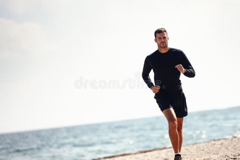 Training for a Big Run. a Handsome Young Man Running on the Beach ...