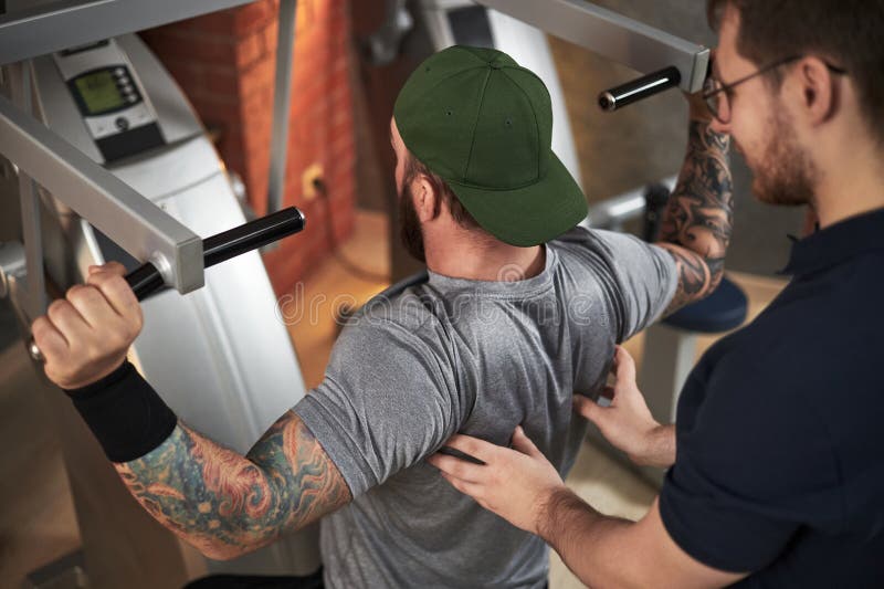 Training in Gym with Personal Trainer Spotting Client Stock Image ...