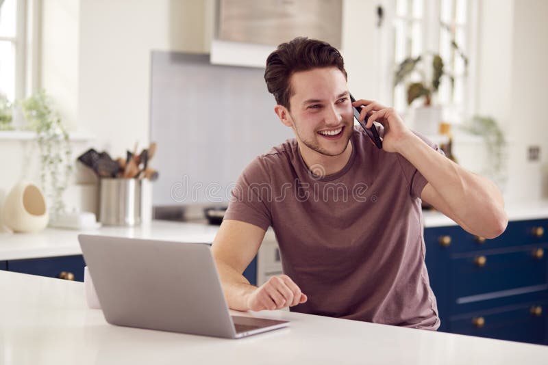 Transgender Man Using Mobile Phone Working from Home Using Laptop on ...