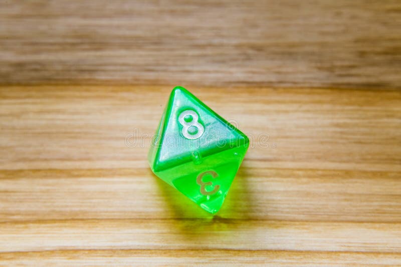 A Translucent Green Eight Sided Playing Dice on a Wooden Background ...