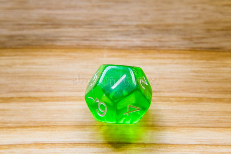 A Translucent Green Twelve Sided Playing Dice on a Wooden Background ...