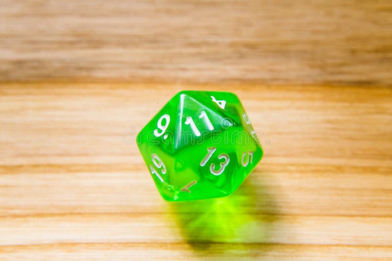 A Translucent Green Twenty Sided Playing Dice on a Wooden Background ...
